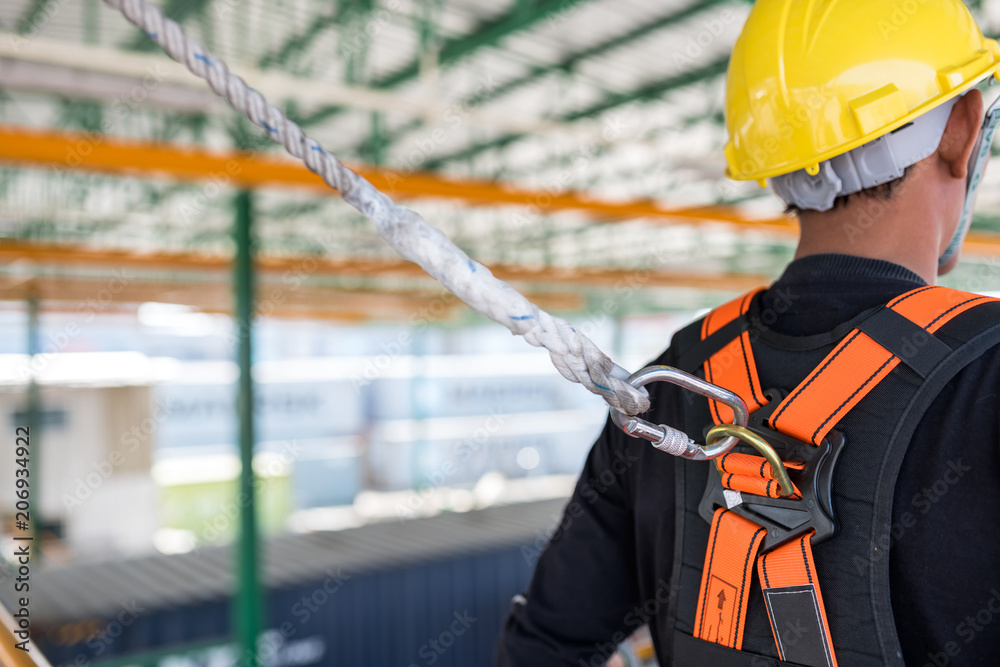 Construction worker wearing safety harness and safety line working on ...
