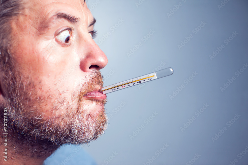 Sick man with thermometer in mouth,looking and worry at thermometer on ...
