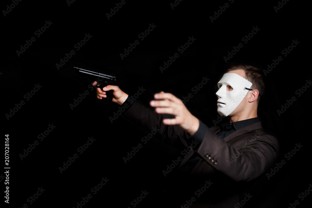 A man in a white mask falls from a gunshot wound with a pistol in his ...
