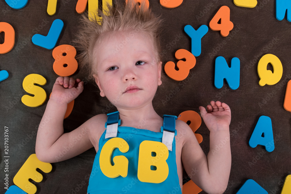 Happy charming Caucasian blond's kid in colored clothes playing with ...