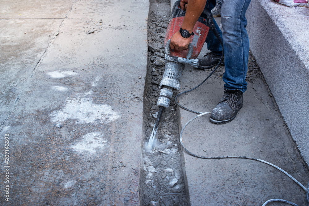 Male worker repairing driveway surface with jackhammer, digging and ...