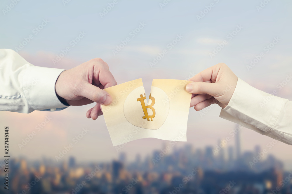 Two hands tear the paper banknote of bitcoin into two part on the ...