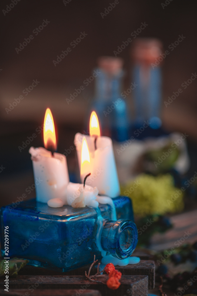 Burning candles on an inkwell in a magical still life with potions and ...