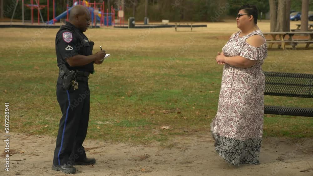 An African American police officer talks with a female citizen who ...