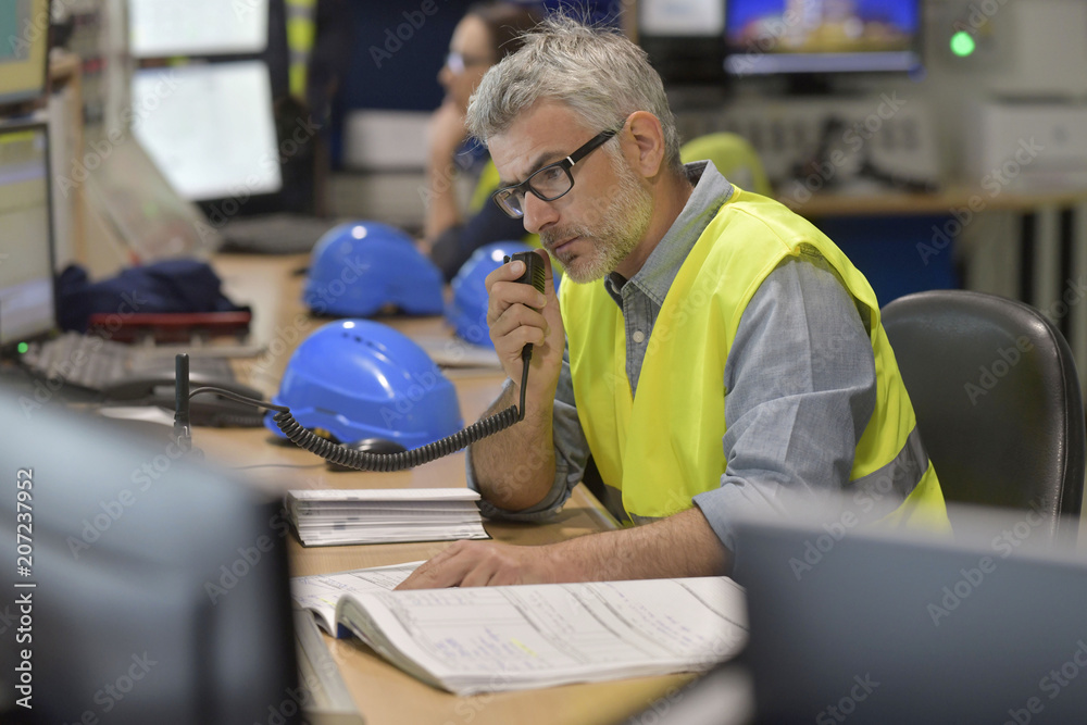 Industrial control room supervisor using radio to give instructions ...