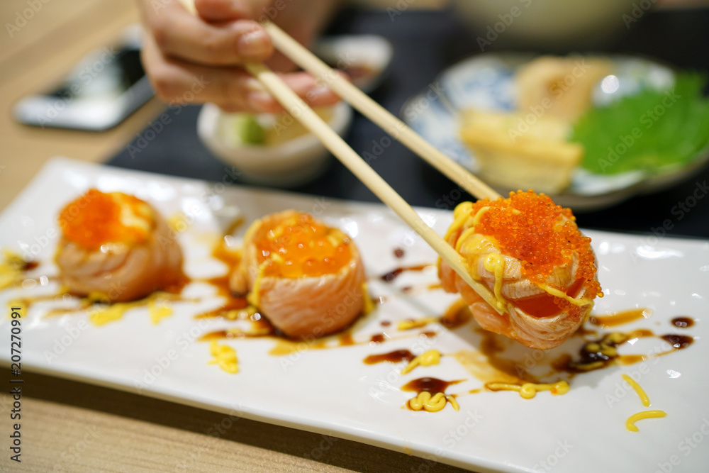 Aburi Salmon Roll - A plate of grilled salmon roll, topped with capelin ...