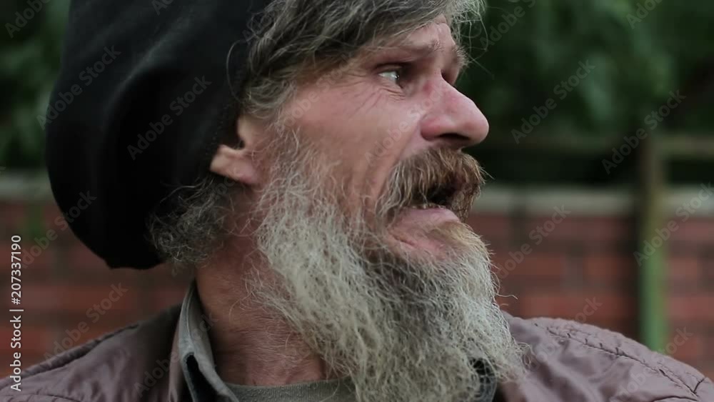 An old man or a homeless man with rotten teeth tells something, close ...