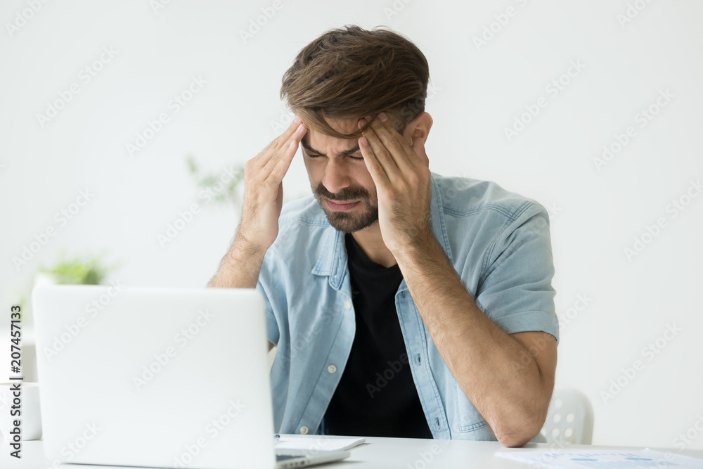 Exhausted male worker massaging head, suffering from severe headache ...