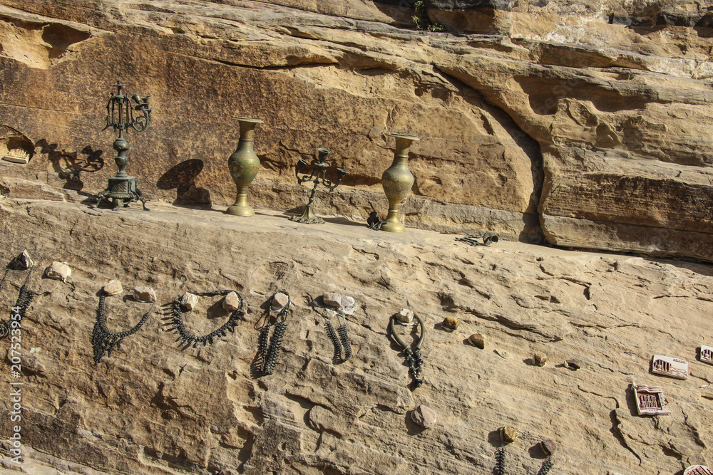 Old jugs, candlesticks and bedouin jewelry on a rock in Little Petra in ...