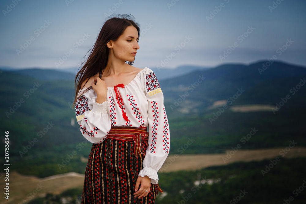 Attractive woman in traditional romanian costume on mountain green ...