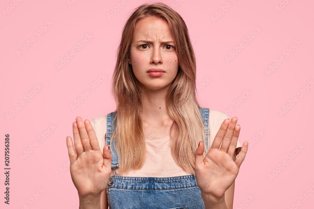 Studio shot of grumpy young female with irritated expression, makes ...