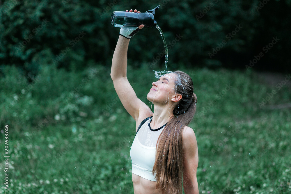 Young fitness girl pouring cold water on face after jog, Close up horizontal face shot. Woman in ...