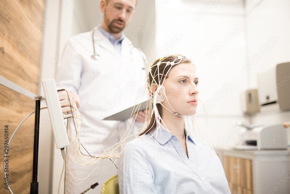 Young patient with electrode on head and her doctor controlling the ...