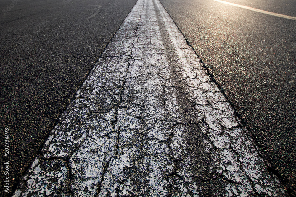 Asphalt road with white strip of the central lane in perspective ...
