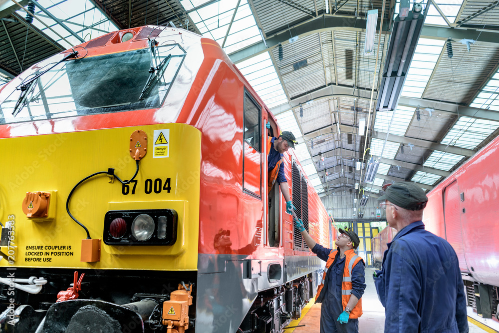 Engineers with refurbished locomotive in train engineering factory ...