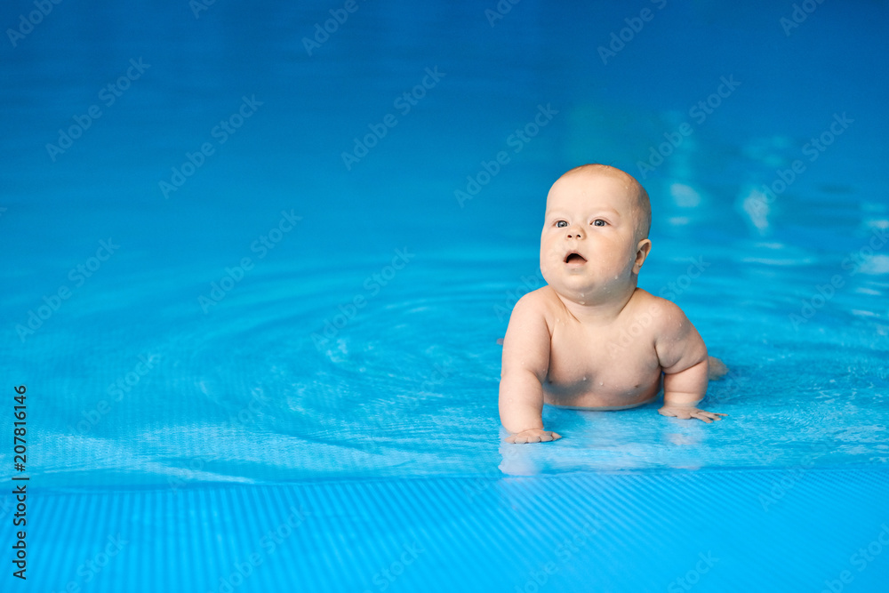 Little baby boy lying in blue swimming pool in water. Activity child ...