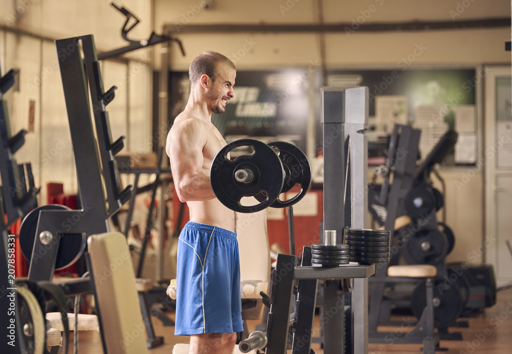 one young shirtless man, weight exercise, gym indoors exercise ...