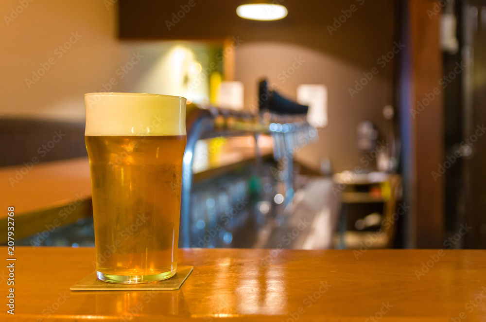 Glass pint of beer on top of bar counter, brewpub, craftbeer. Stock ...