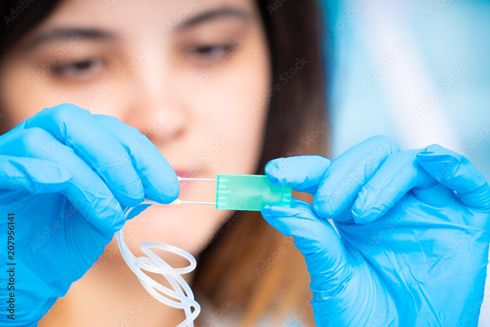 technician girl with microfluidic device LOC in microbiological lab ...