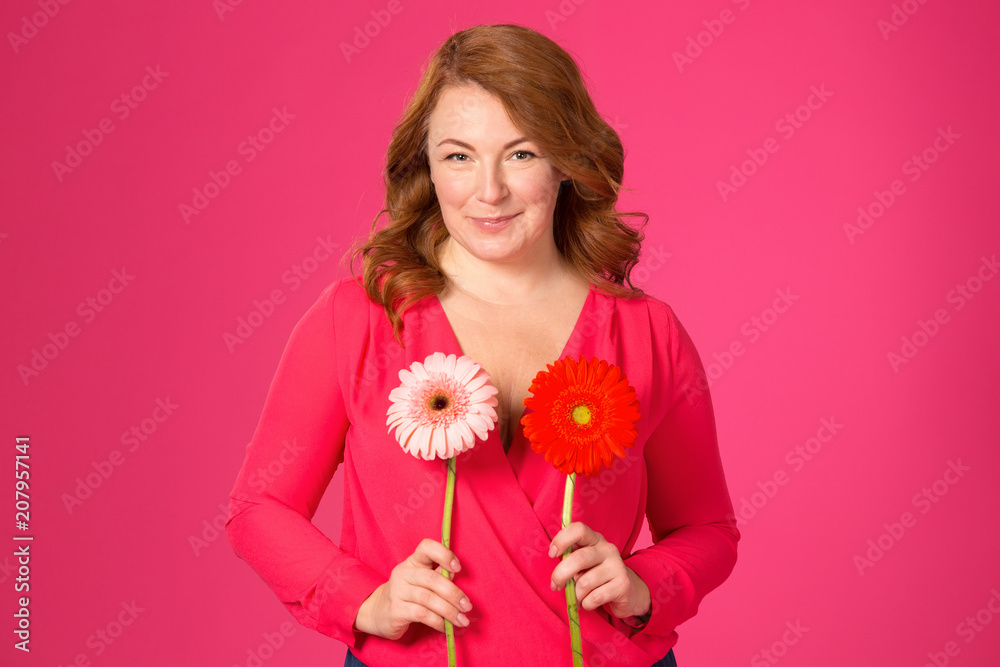 Beautiful adult woman with flowers on a pink background. Woman holding ...