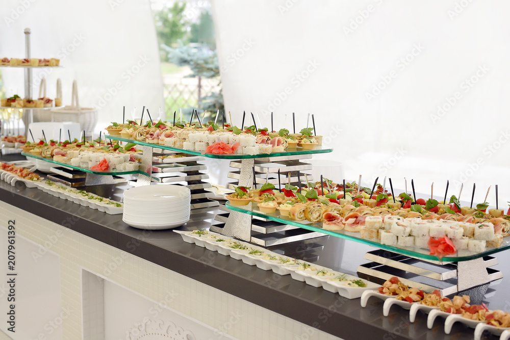 buffet table of snacks with sushi canapes and salads, catering service ...