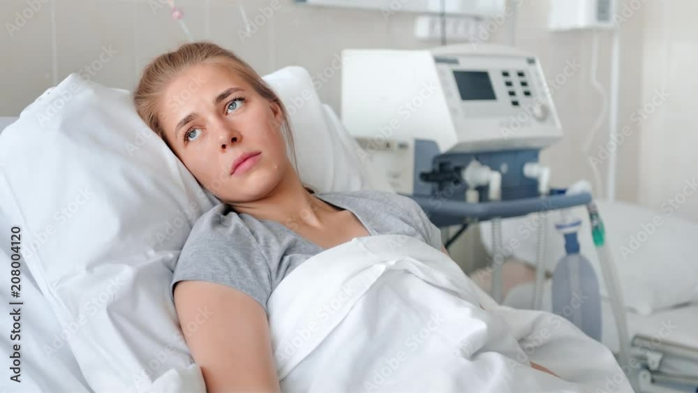 A sick young woman lying in a hospital bed and waiting a doctor Stock ...