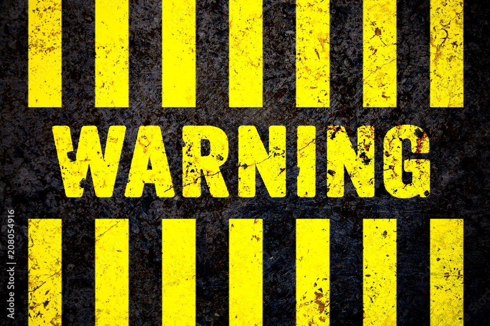 Warning sign with yellow and black stripes painted over cracked ...