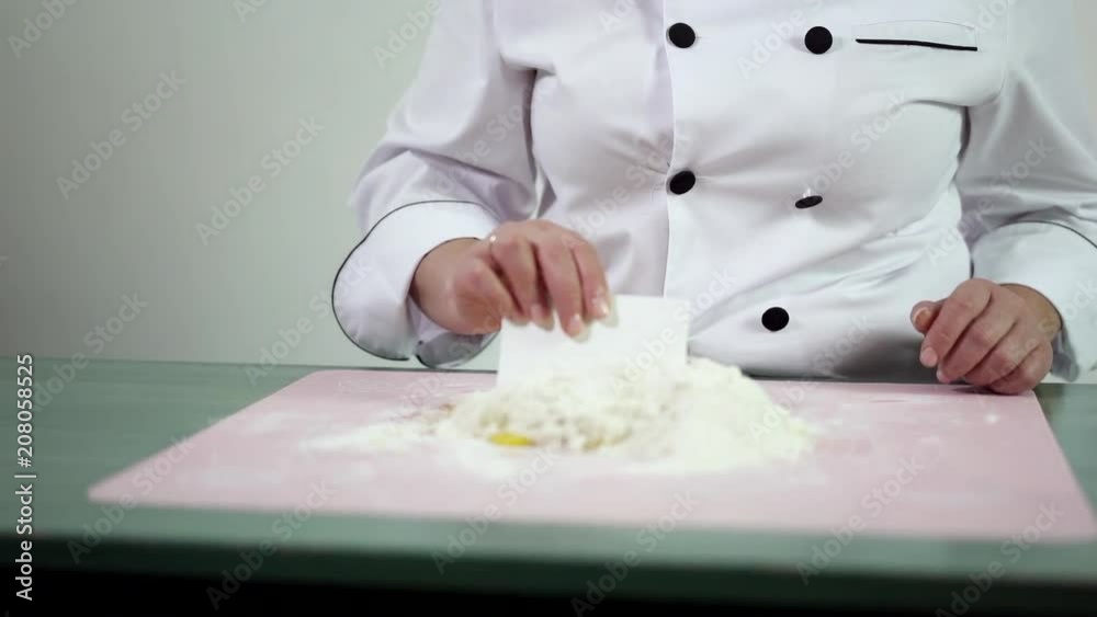 Young professional baker kneading dough consisted of wheat flour and ...