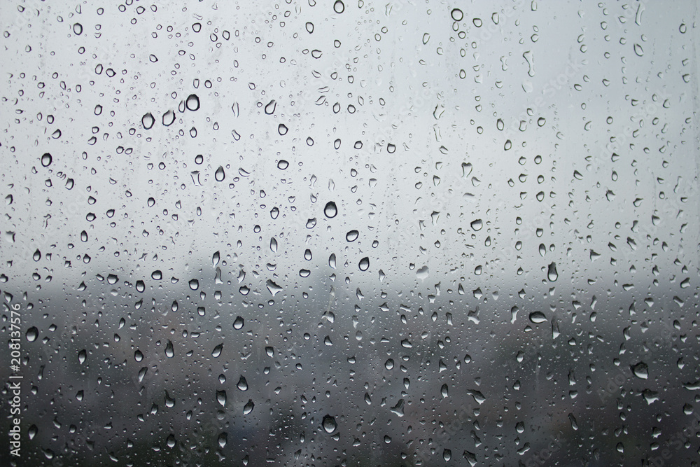 Depression and dreary sad weather shown as water droplets on a window ...