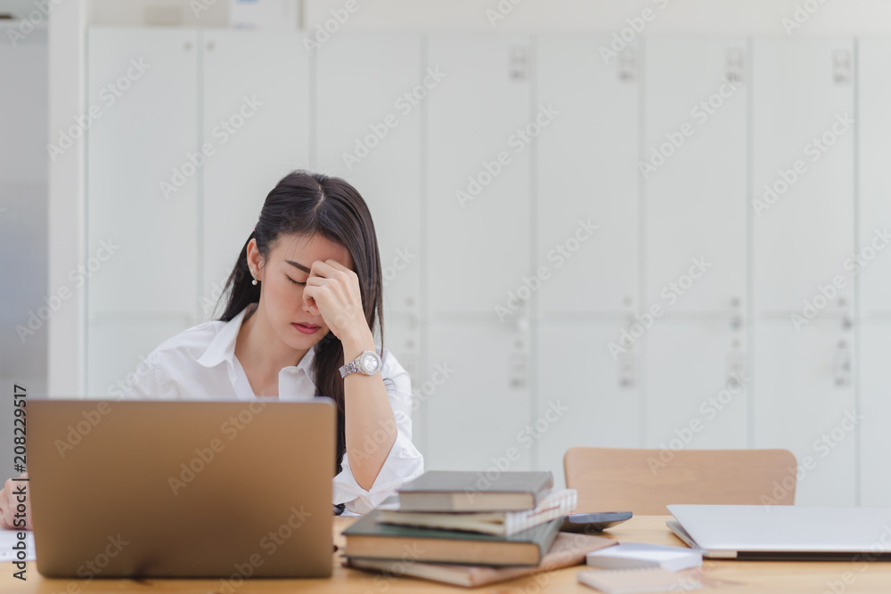 Stressed asian young business woman working with laptop and holding ...