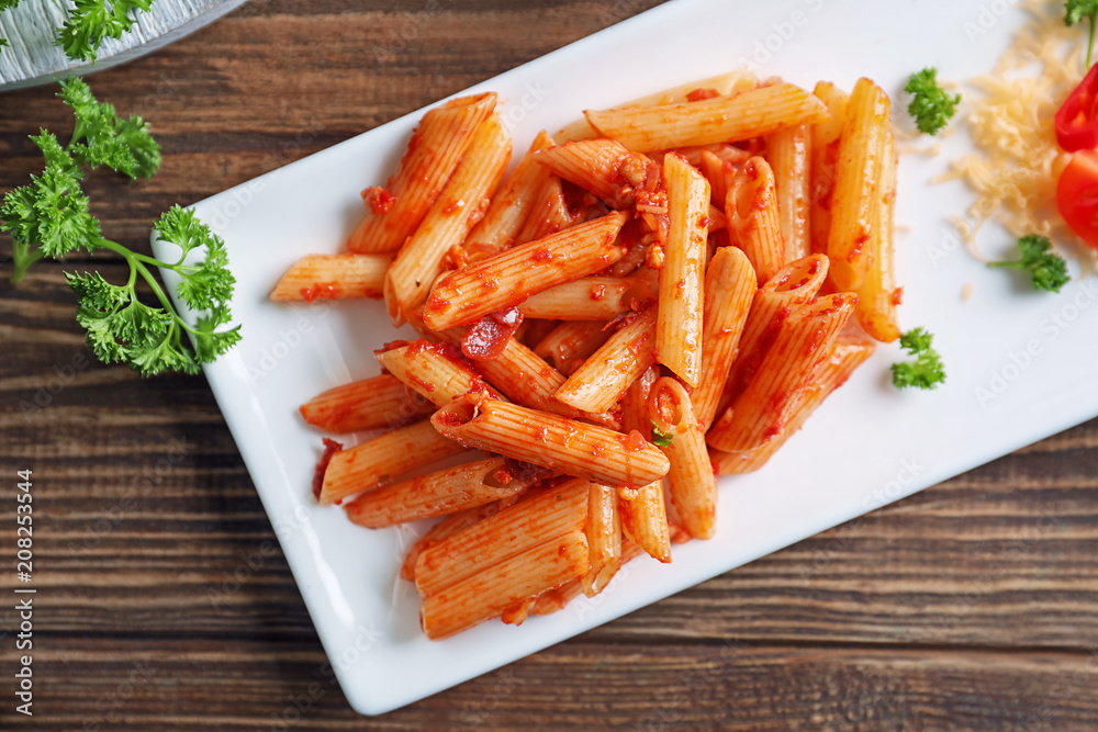 Plate of tasty penne pasta with tomato sauce on wooden table, top view ...