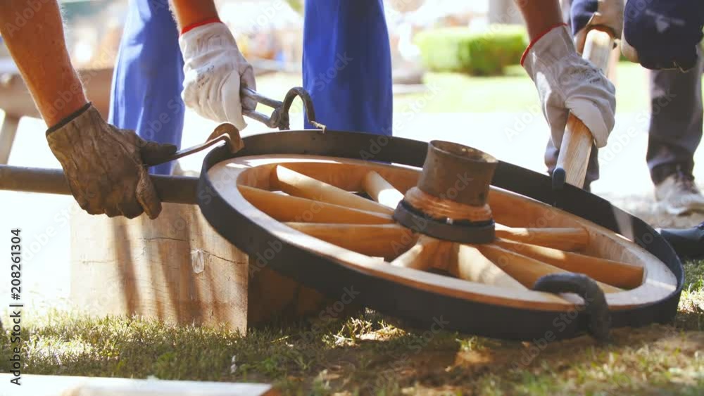 Vidéo Stock Blacksmith attach iron ring around wooden carriage wheel ...