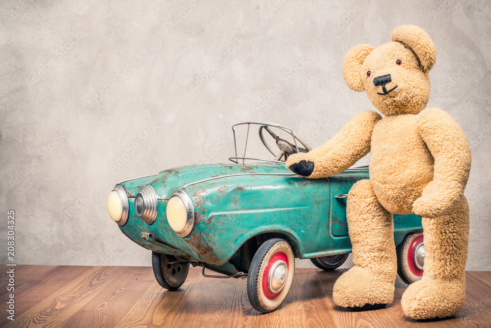 Teddy Bear standing near rusty outdated retro turquoise toy pedal car ...