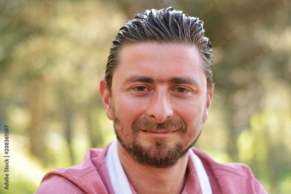 Young man's outdoors portrait looking at the camera with natural green ...
