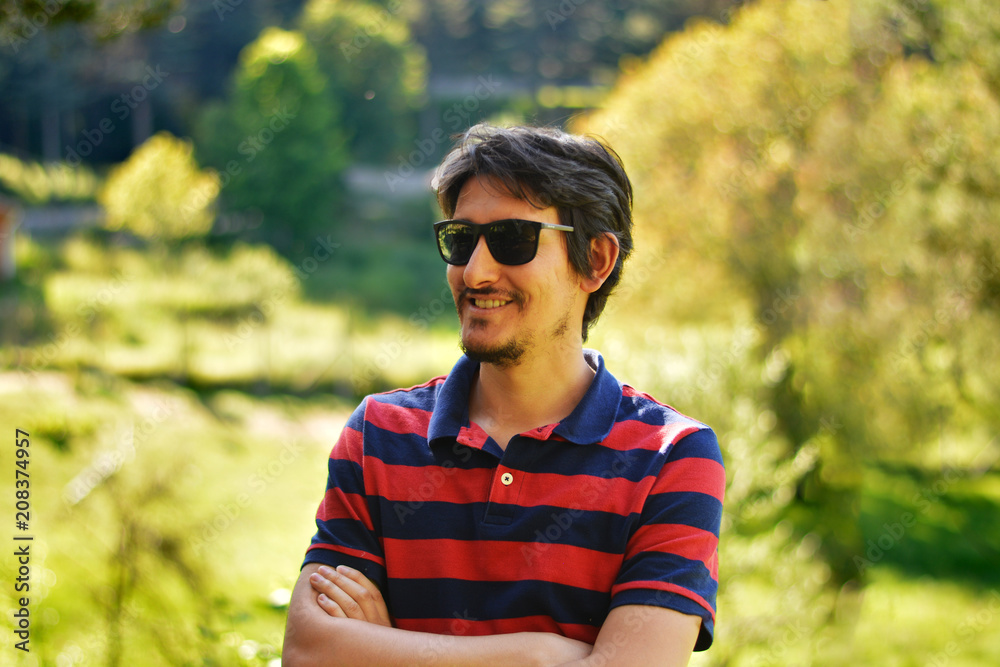 Young man's outdoors portrait looking at the camera with natural green ...