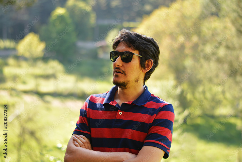 Young man's outdoors portrait looking at the camera with natural green ...