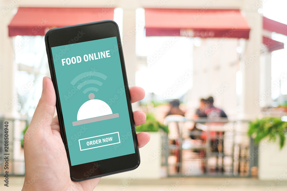 Hand holding smart phone with food online device on screen over blur ...