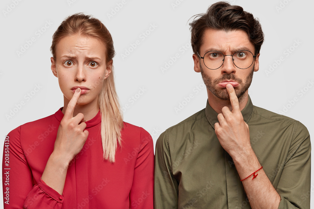 Puzzled woman and man look with displeasure at camera, has displeased ...