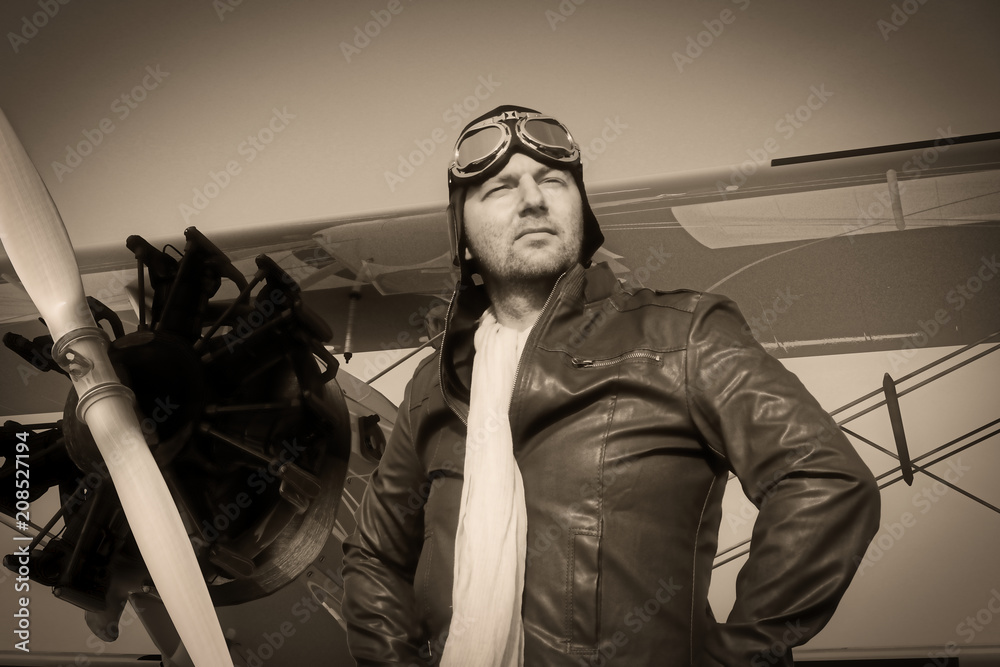 Portrait of a vintage pilot with leather cap, scarf and aviator glasses ...