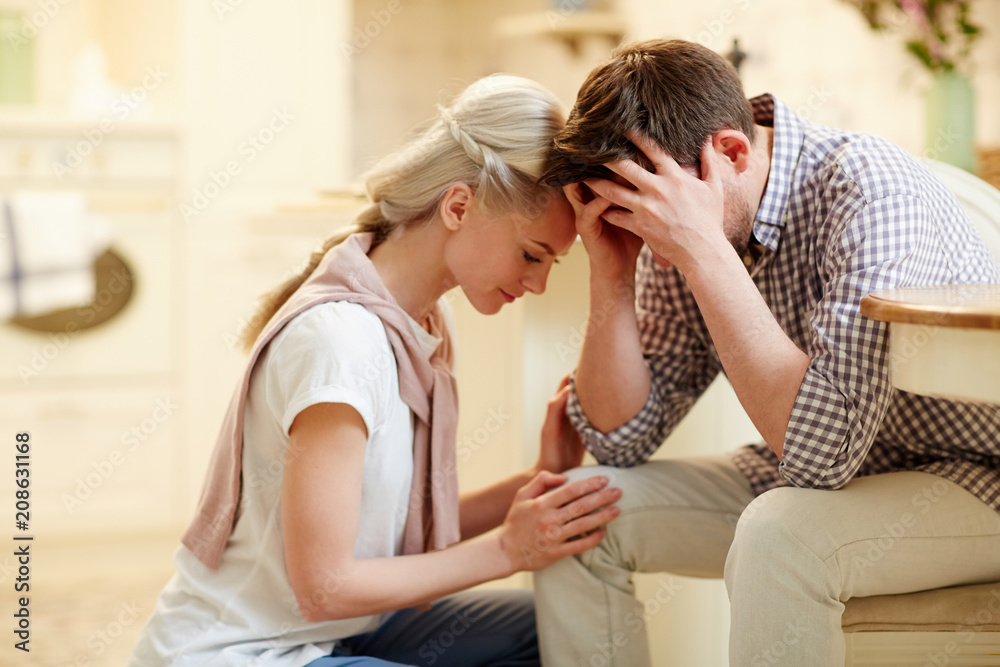 Young woman supporting her worried husband having troubles at work ...