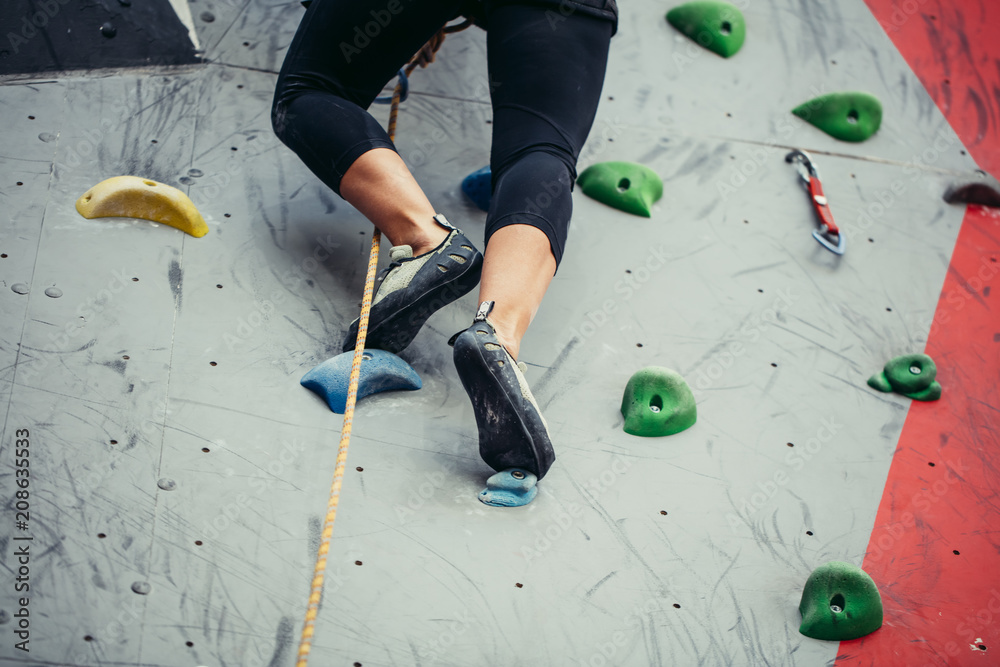 Cropped view of sportswoman rock climber leggs climbs on a rocky wall ...