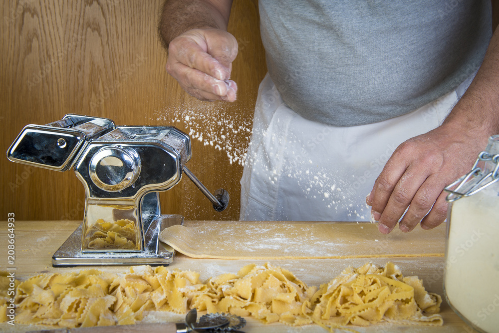 Chef de cocina italiano haciendo pasta fresca con una máquina sus manos ...