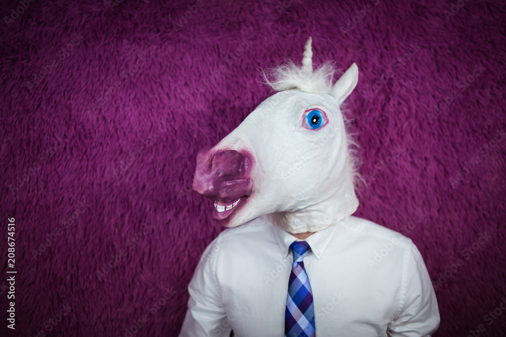 Freaky young man in comical mask stands on the purple background ...