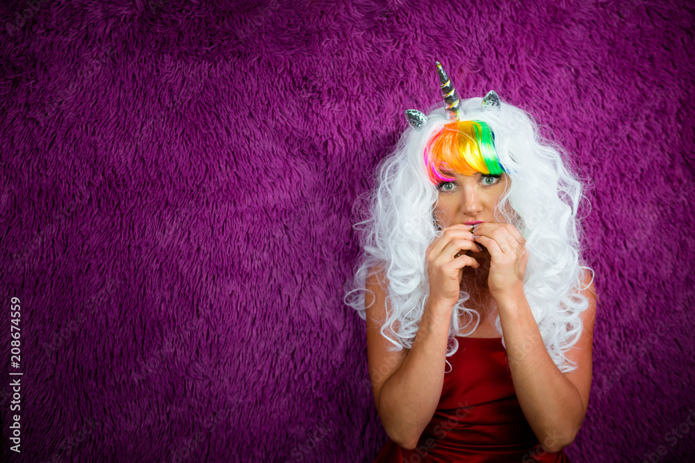 Freaky young woman in unusual wig stands on the purple background ...