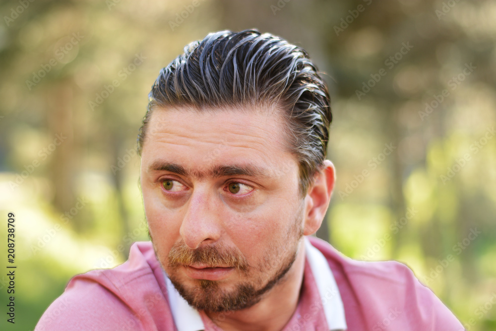 Young man's outdoors portrait looking at the camera with natural green ...