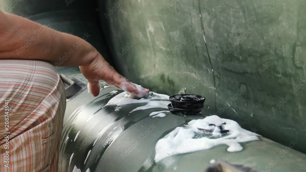 checking the valve of a green rubber inflatable boat. The old female ...