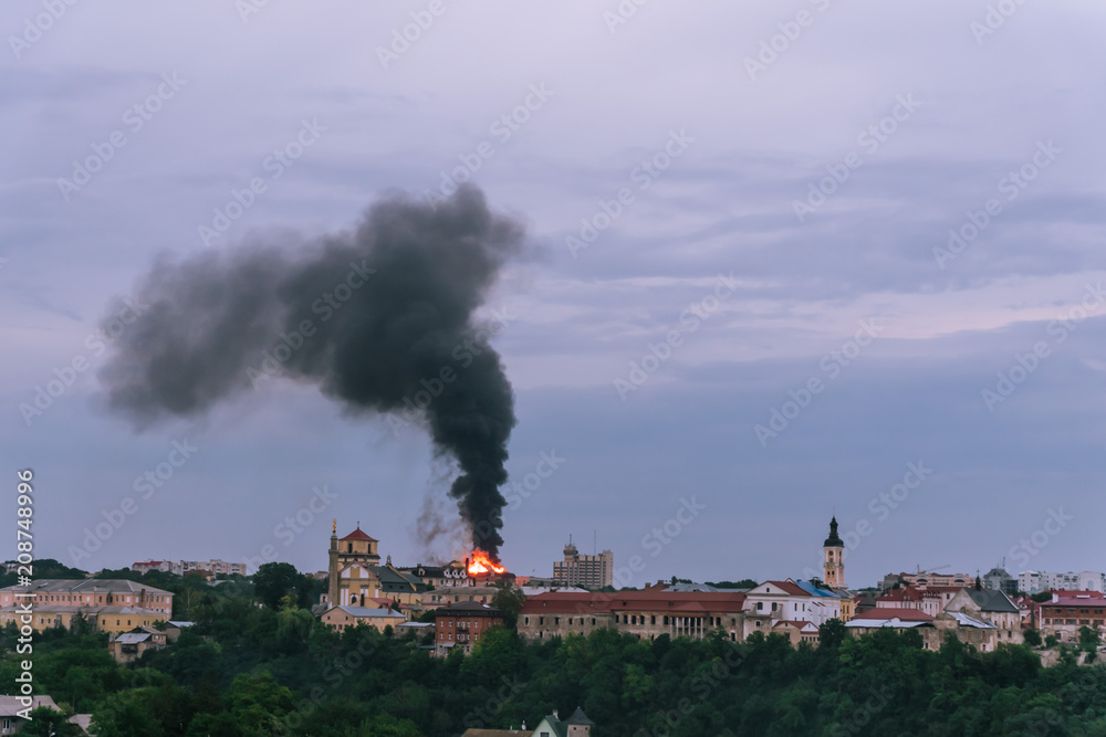 a view of a small town, from a distance, the city burns a house, black ...