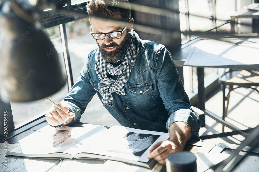 Serious man architect with dark hair and beard, weared in denim jacket ...