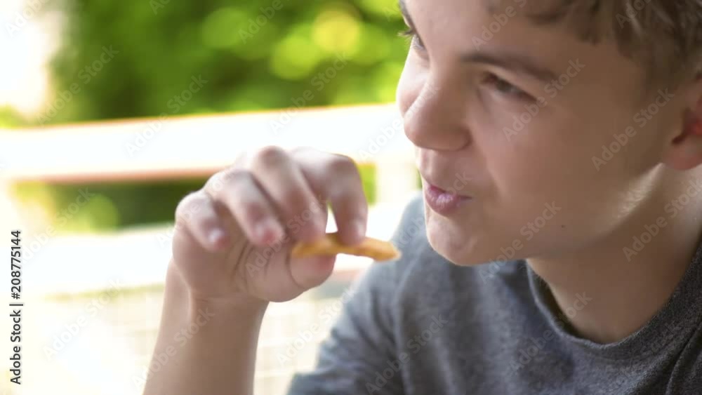 Young happy teenager eating tasty hamburger in fast food restaurant ...