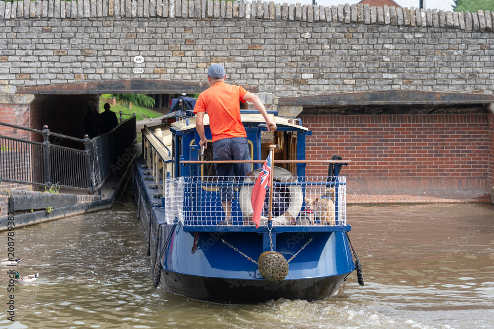 blue and cream canal boat being driven through small gap in tunnel ...